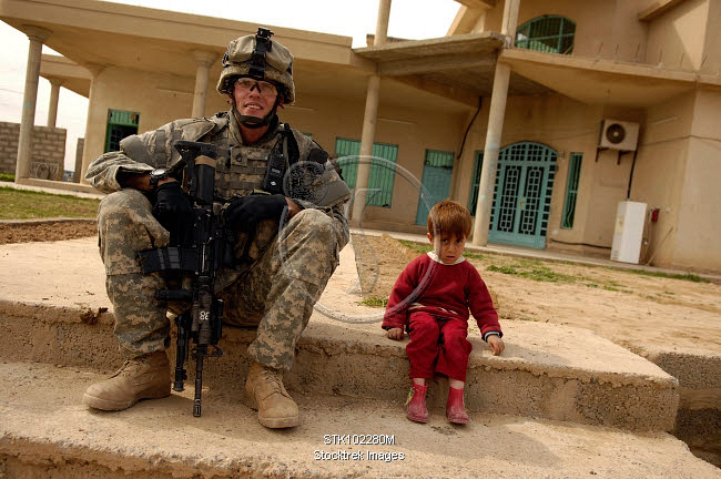 U.S. Army Sergeant sits next to an Iraqi boy. | Stocktrek Images