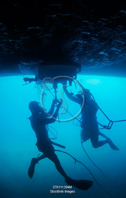 U.S. Navy divers conduct a ship's husbandry dive on USS Hue City ...