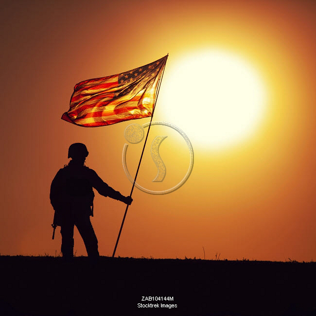 Silhouette of a U.S. Army soldier standing on sunset horizon, waving ...